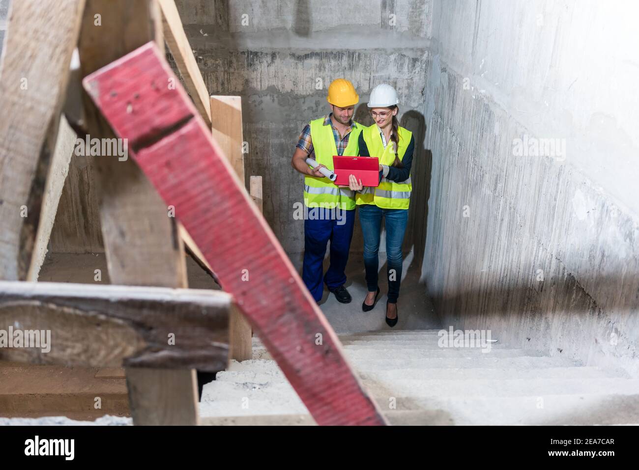 Construction worker and builder inspecting stairs in building shell ...