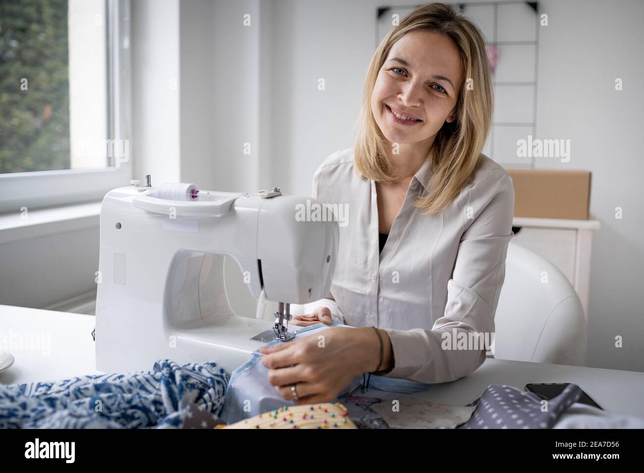 Caucasian fashion designer sitting in her studio with her sewing ...