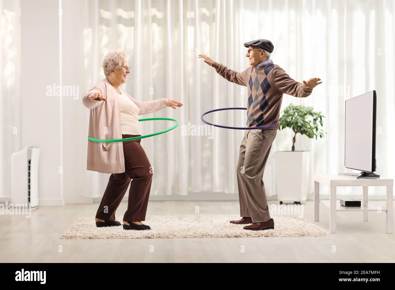 Happy elderly couple spinning hula hoops at home in a living room Stock ...
