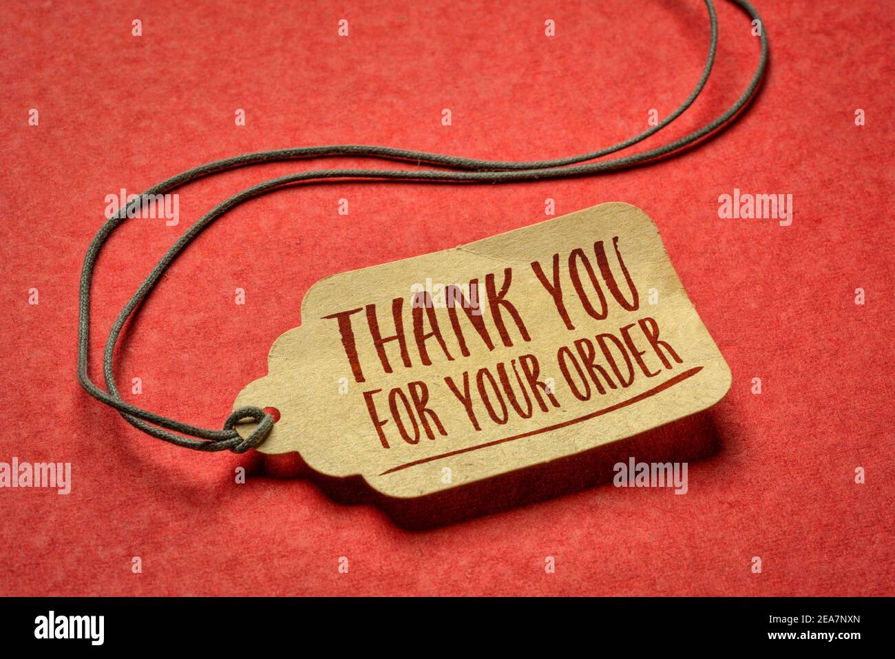 thank you for your order - sign a paper price tag against textured red ...