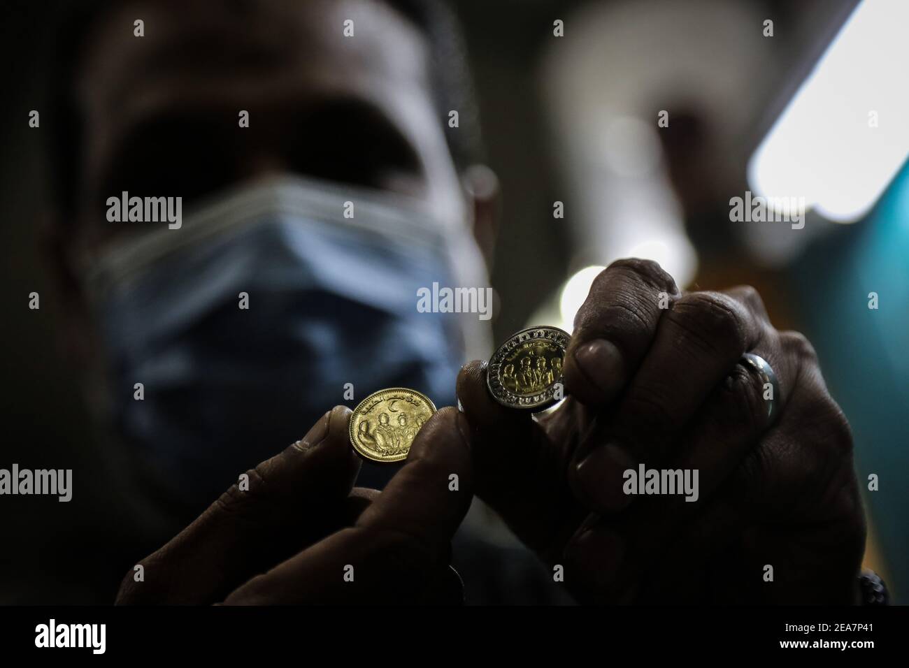 Cairo, Egypt. 08th Feb, 2021. A worker holds an Egyptian 50pt coin (L ...