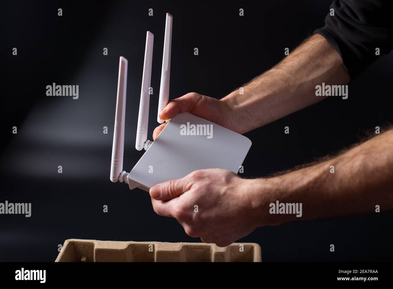 Man's hands holding new wifi router on black background. Unpacking new ...