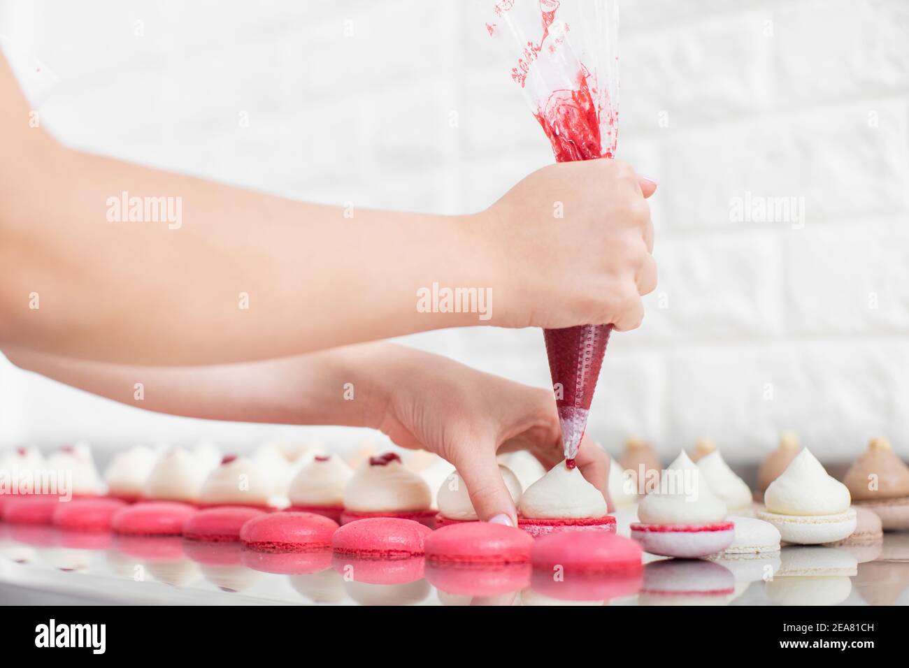 Filling macarons with ganache cream and fruit jam. Close up cropped ...