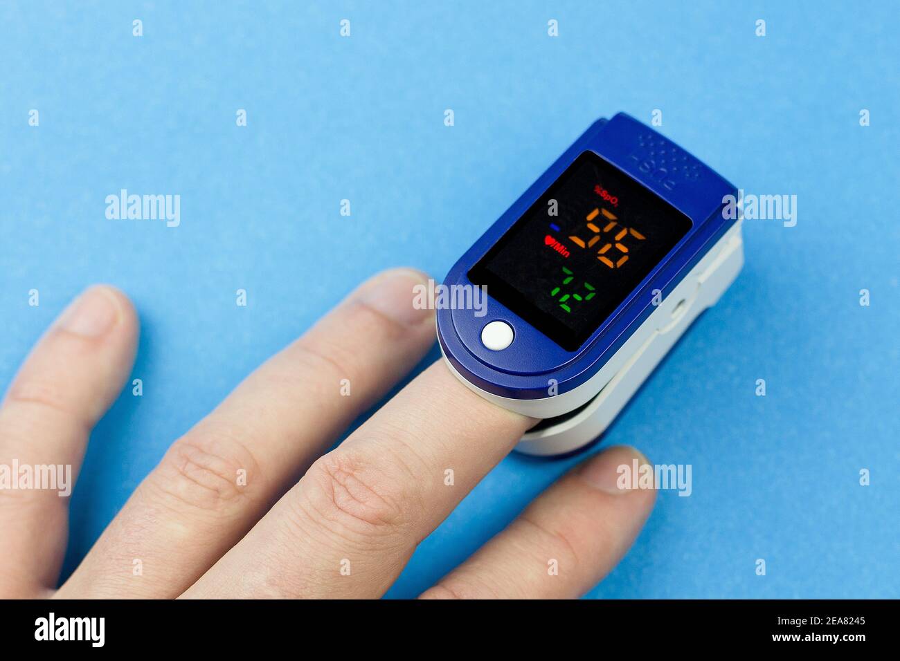 Oximeter on the finger of a man's hand on a blue background Stock Photo ...