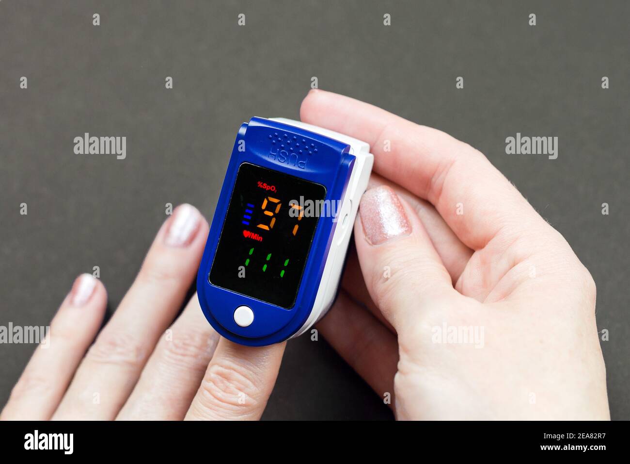 Oximeter on the finger of a female hand, black background Stock Photo ...