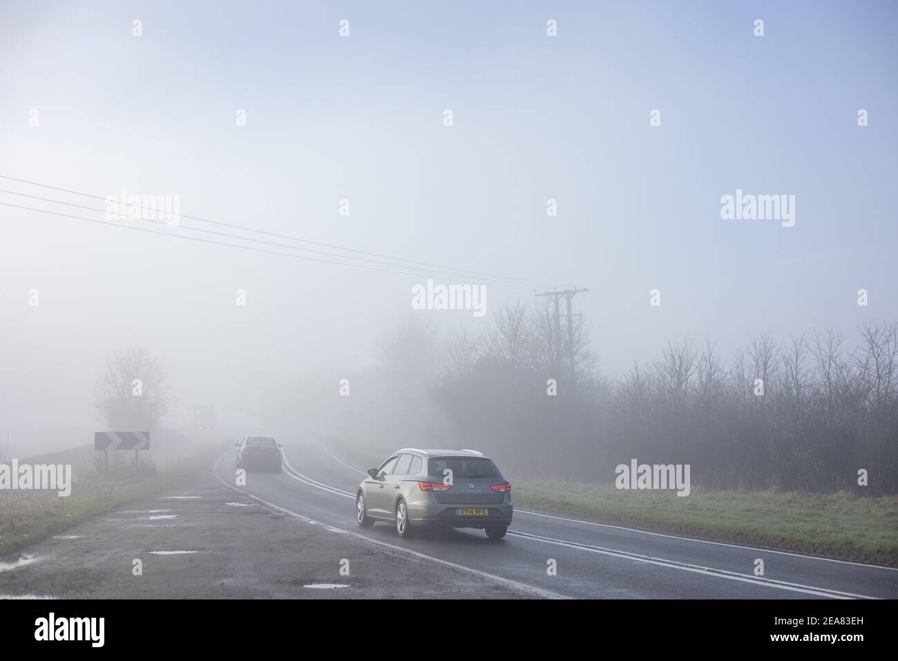 Cars disappear into thick fog. A trucks headlights are barely visible ...