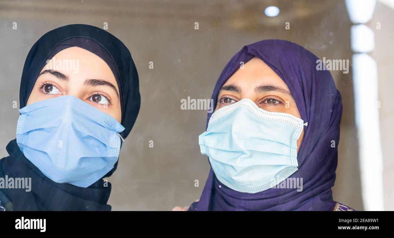 Arabic woman looking from the window during quarantine time and wearing ...