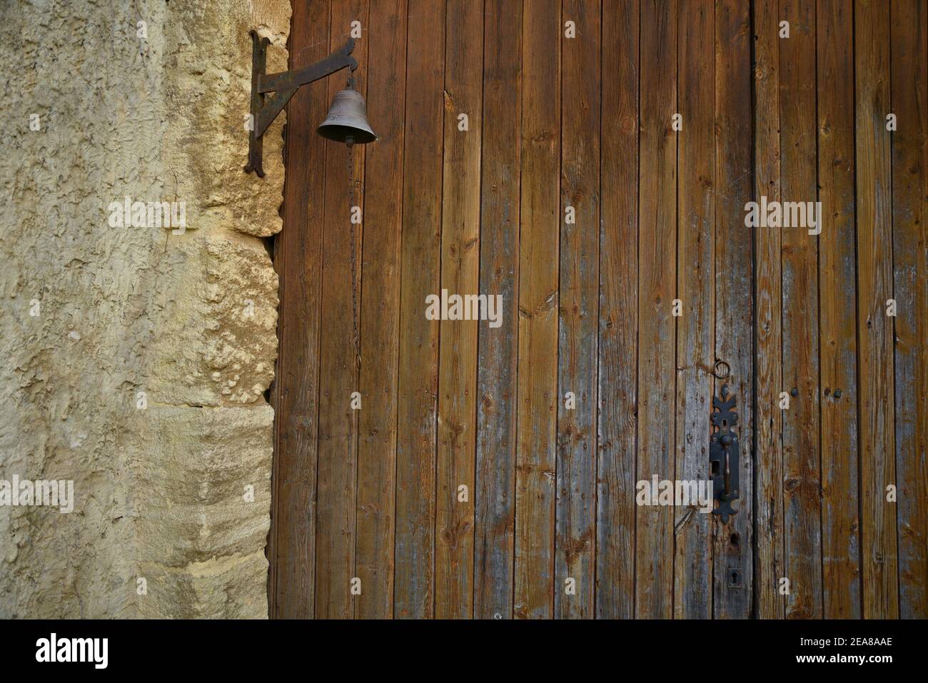 Old rustic wooden door with a hanging doorbell on a stone wall in ...