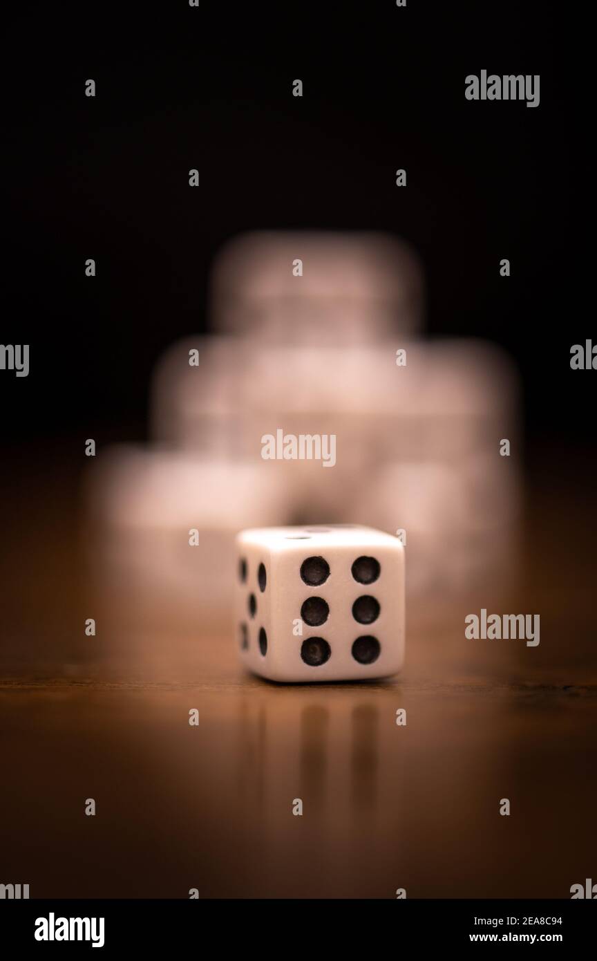 Isolated dice showing a six in front of stack of dice on dark ...