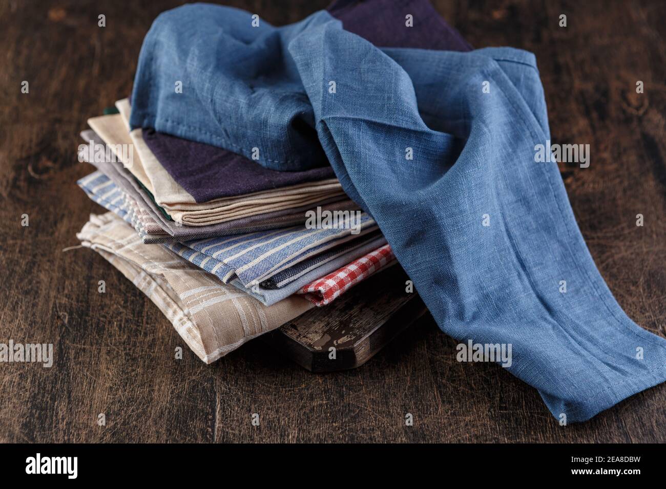 Stack of textile linen napkins of various colors on a dark background ...