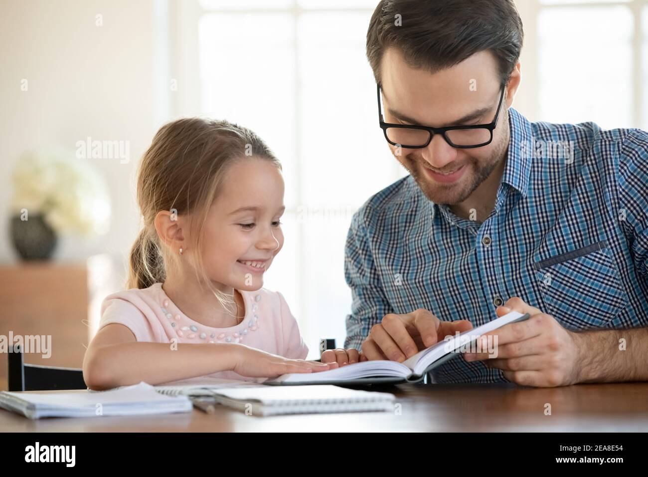 Happy dad and little daughter study reading book Stock Photo - Alamy
