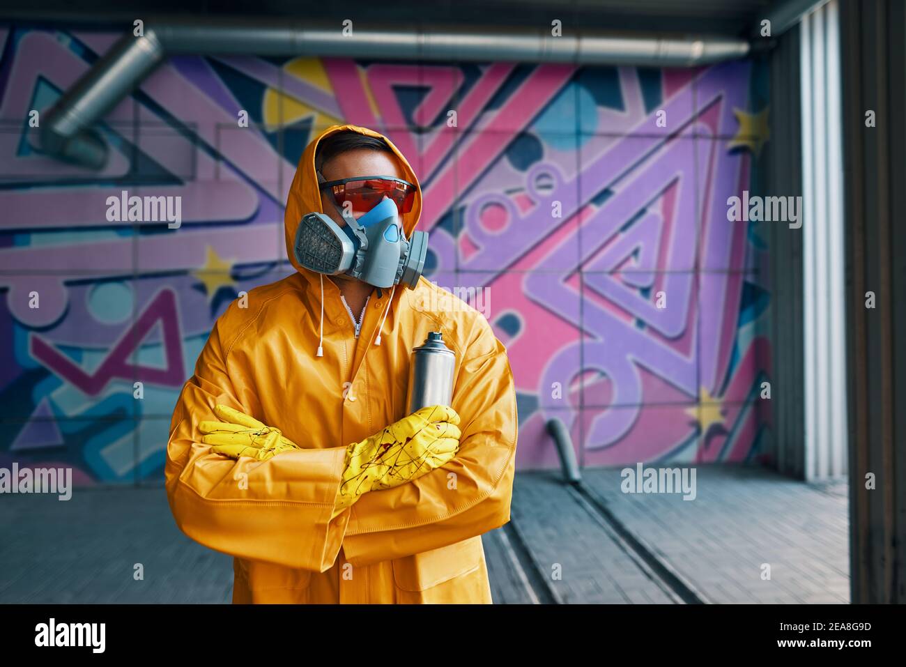 Graffiti painter in respirator mask standing near the wall with his ...