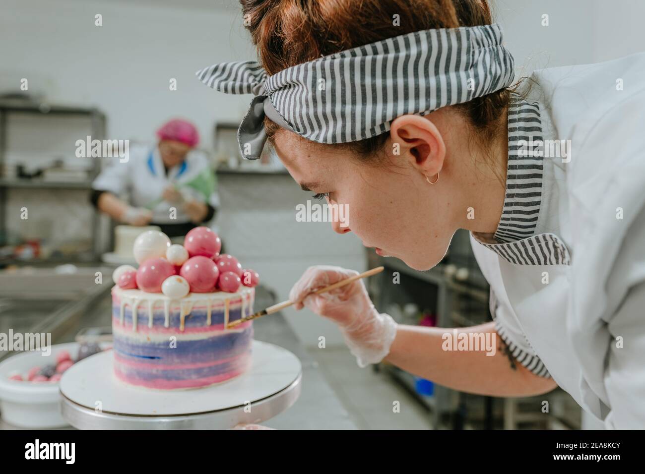 Close up of female confectioner decorating birthday cake using edible ...