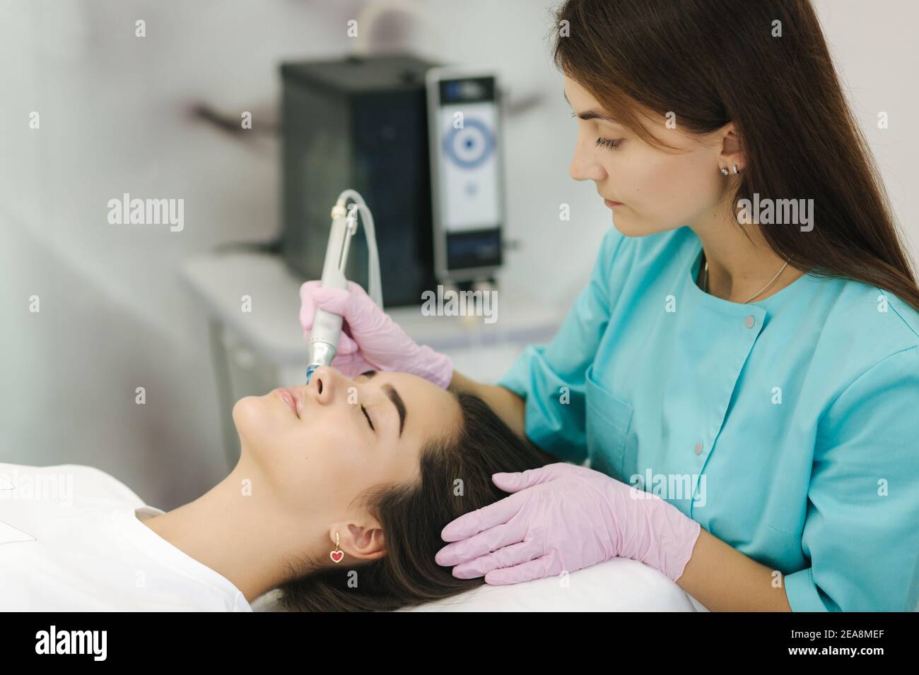 Professional female cosmetologist doing hydrafacial procedure for ...