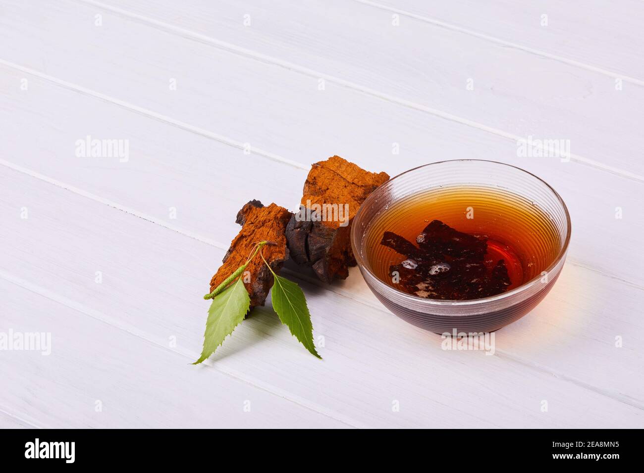 Chaga mushroom pieces, glass tea bowl decorated with green birch leaves ...