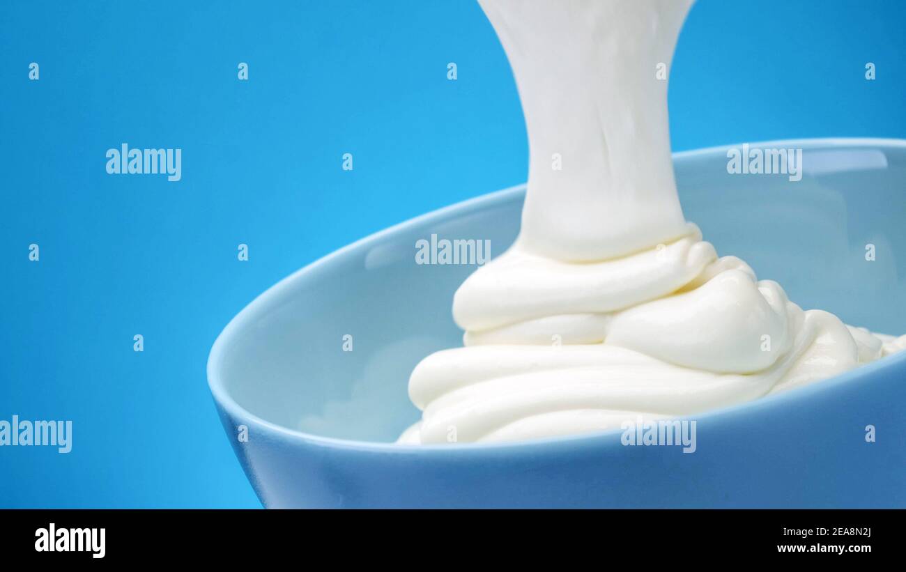 Flowing fresh greek yogurt on blue background Stock Photo - Alamy