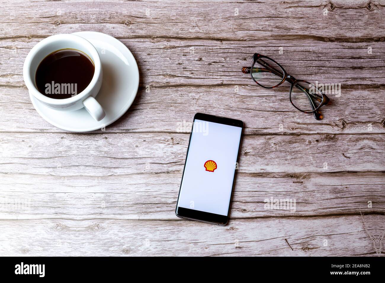 A mobile phone or cell phone laid on a wooden table with the Shell app ...