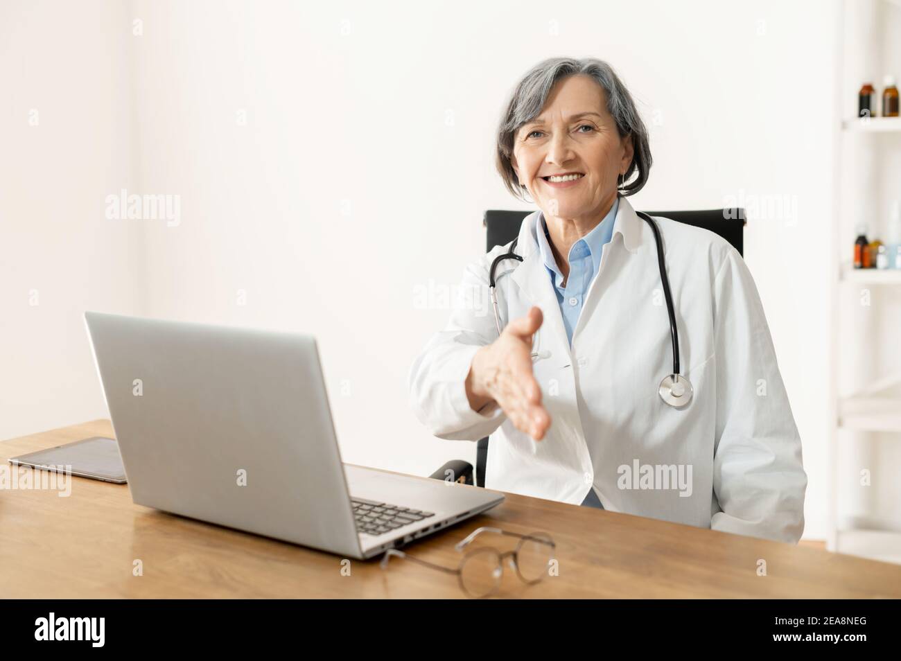 Senior old female doctor with stethoscope wearing lab coat sitting at ...
