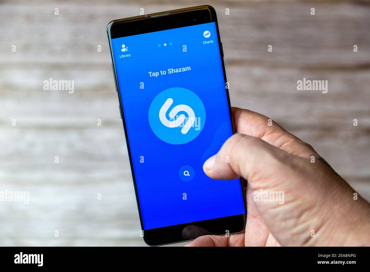 A mobile phone or cell phone being held in a hand with the Shazam app ...