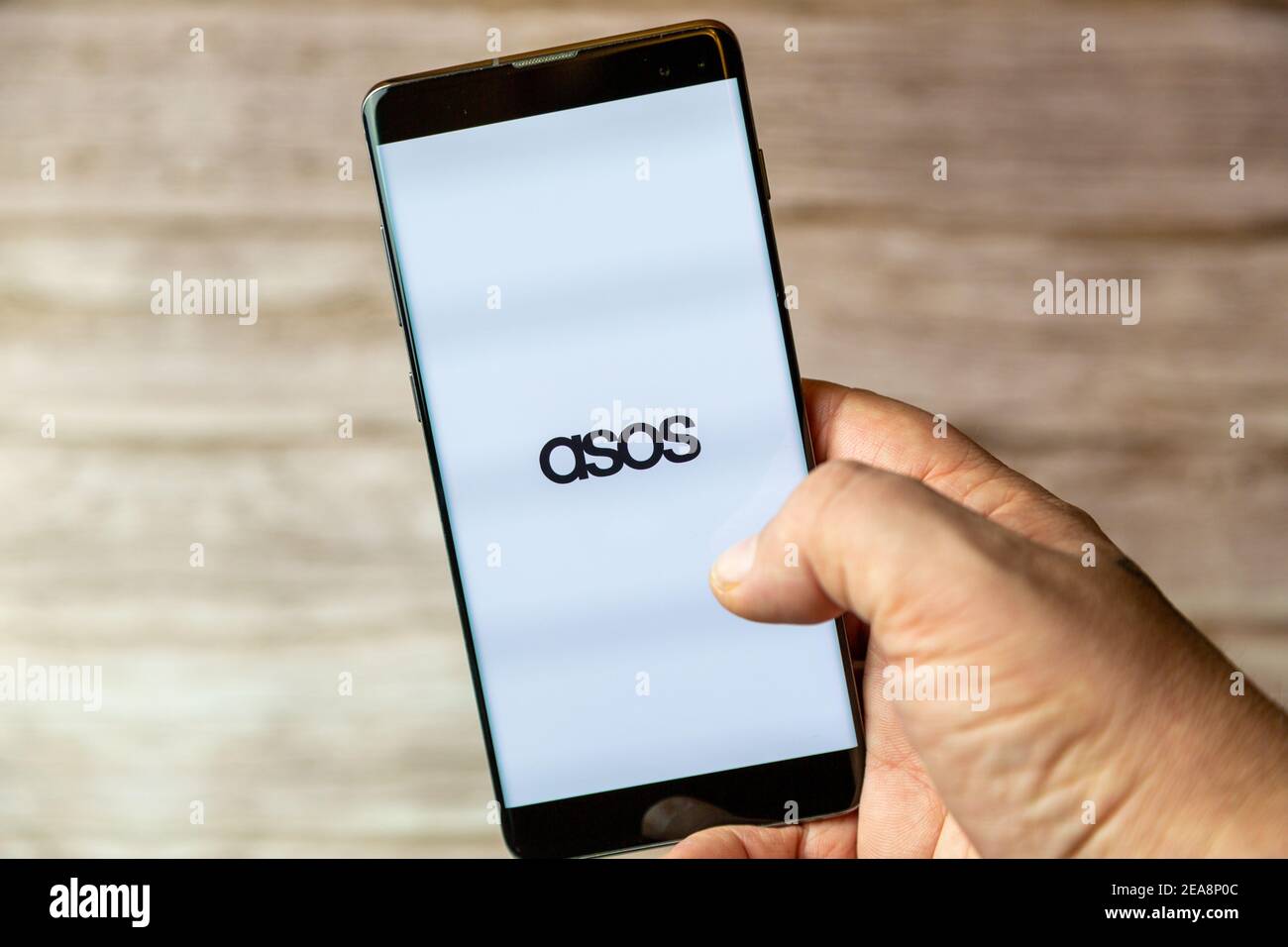 A mobile phone or cell phone being held in a hand with the ASOS app ...
