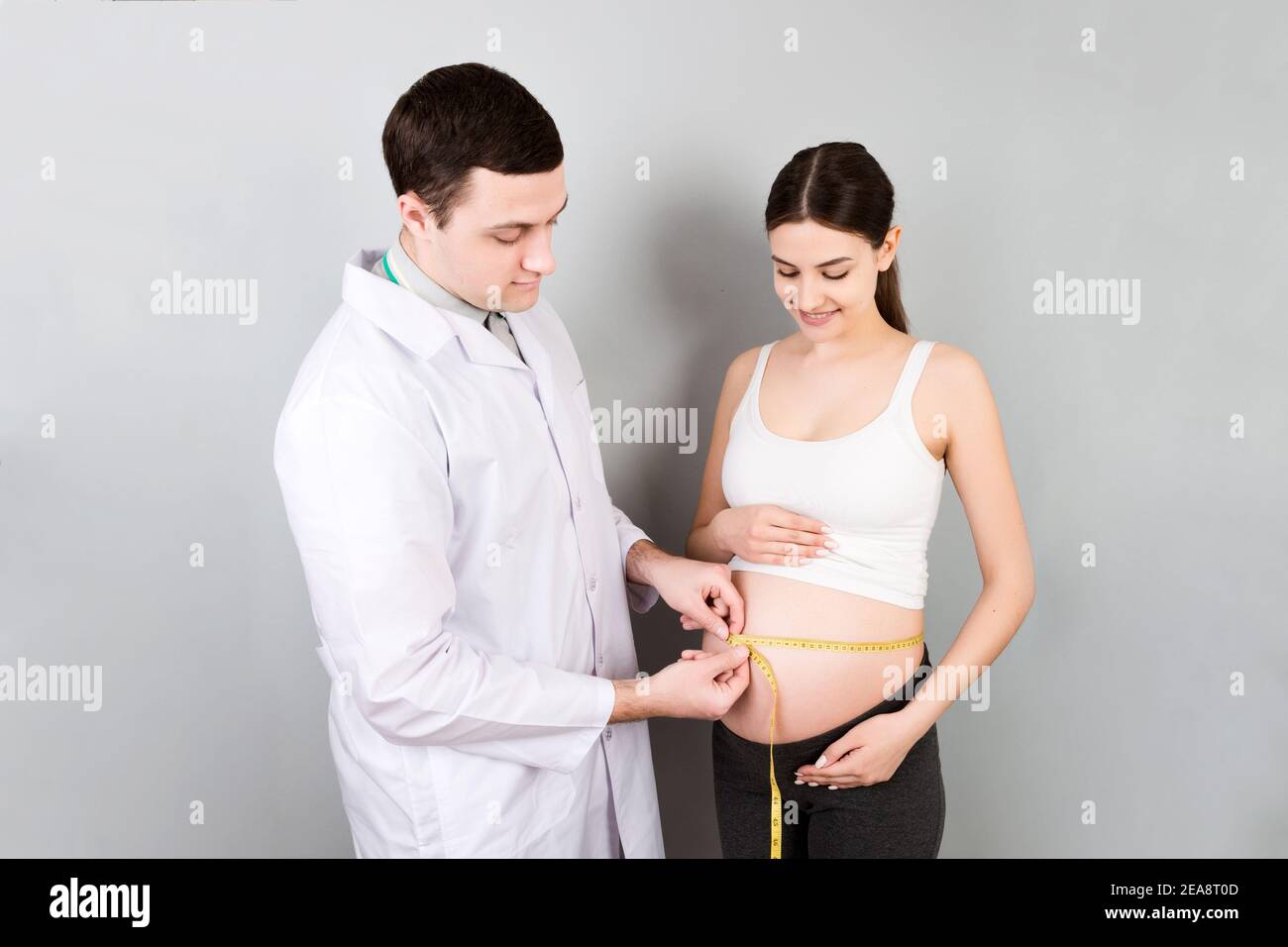 happy beautiful pregnant young woman touching her bare tummy while a ...