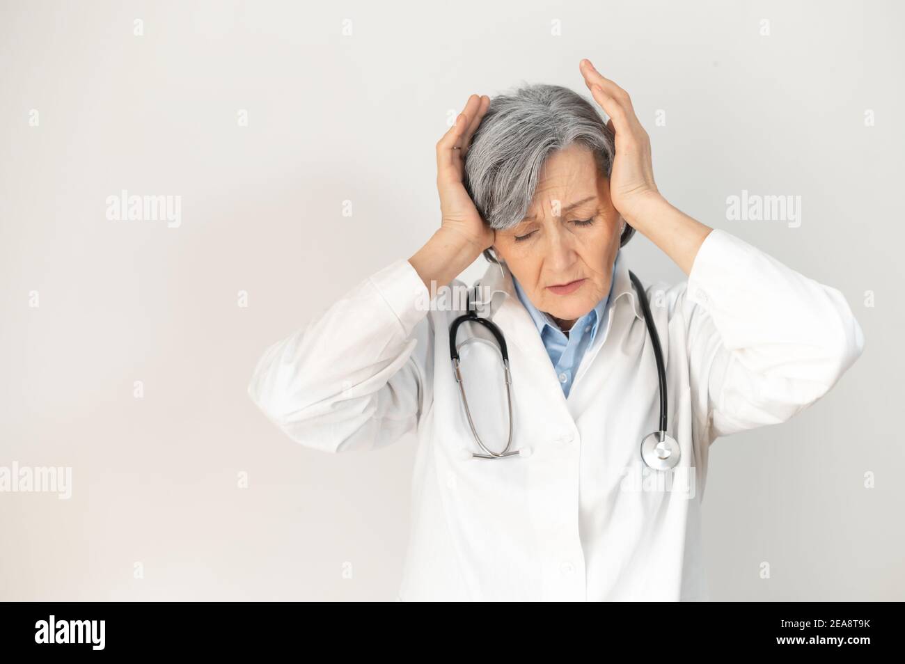 Stressed senior mature doctor with a stethoscope in a medical robe ...
