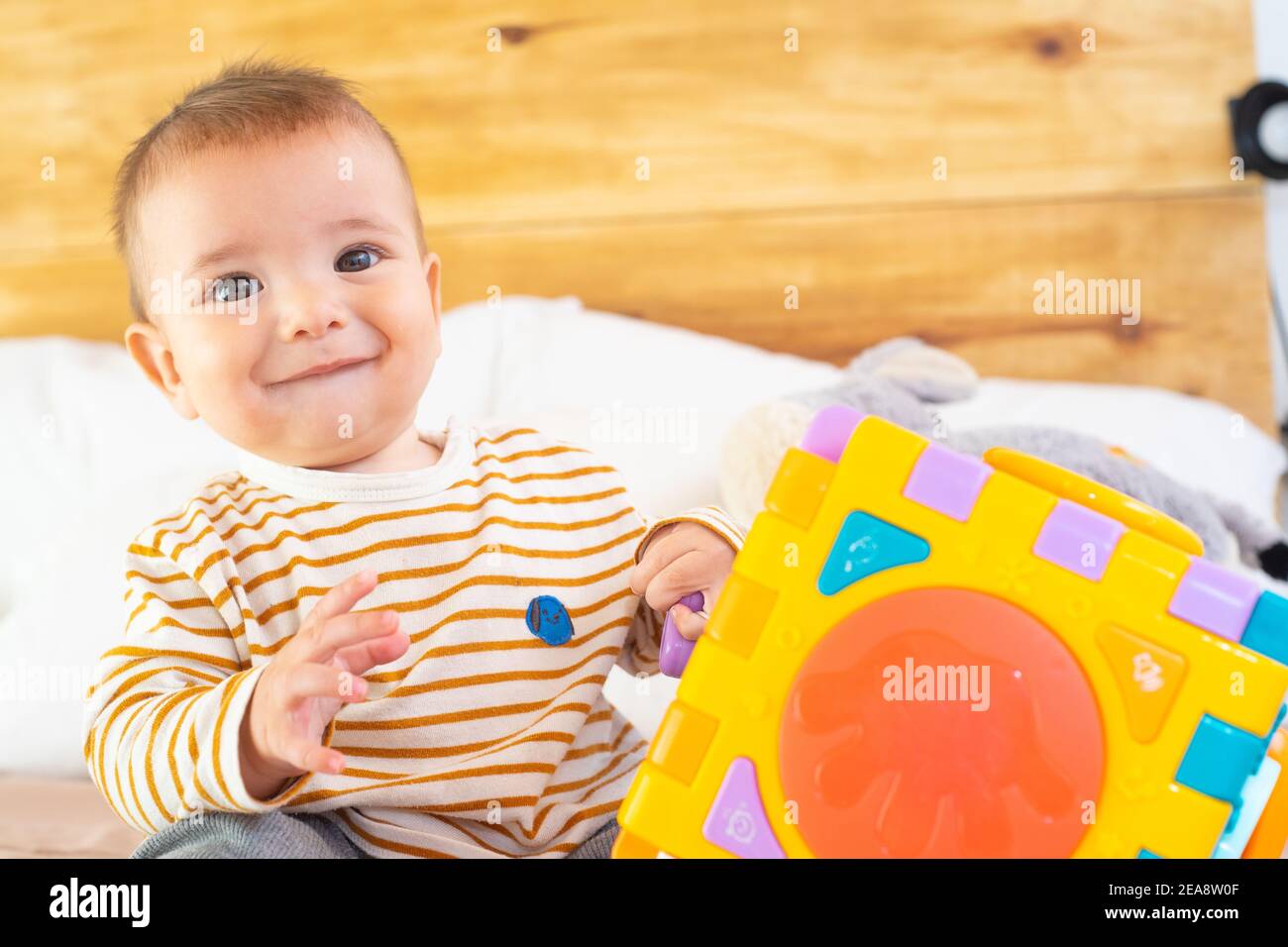 Closeup shot of a cute happy baby playing with a toy on a bed Stock ...