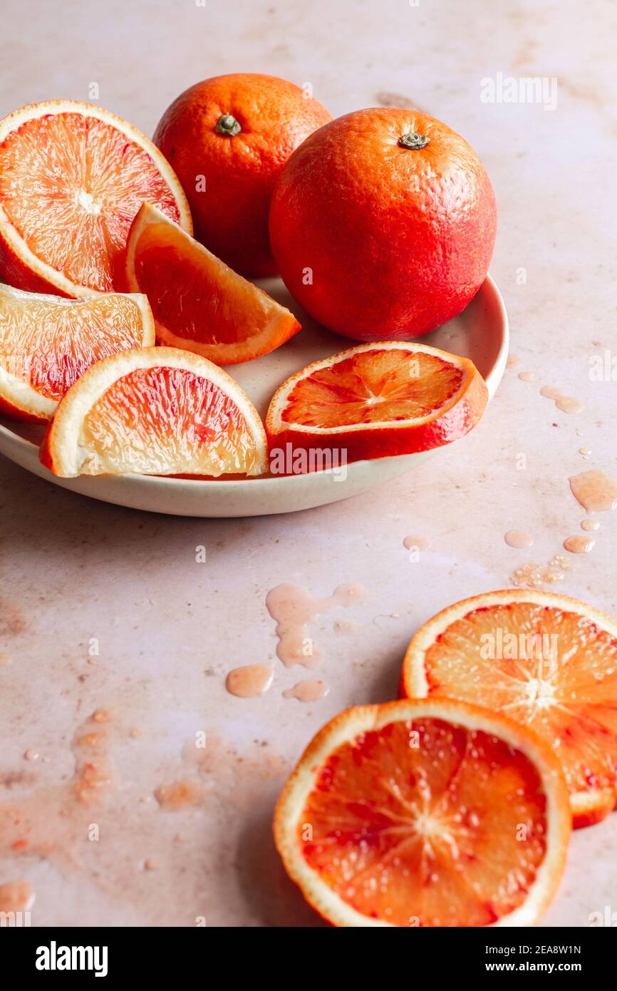 Plate of fresh blood oranges, one whole, some halved, sliced or ...