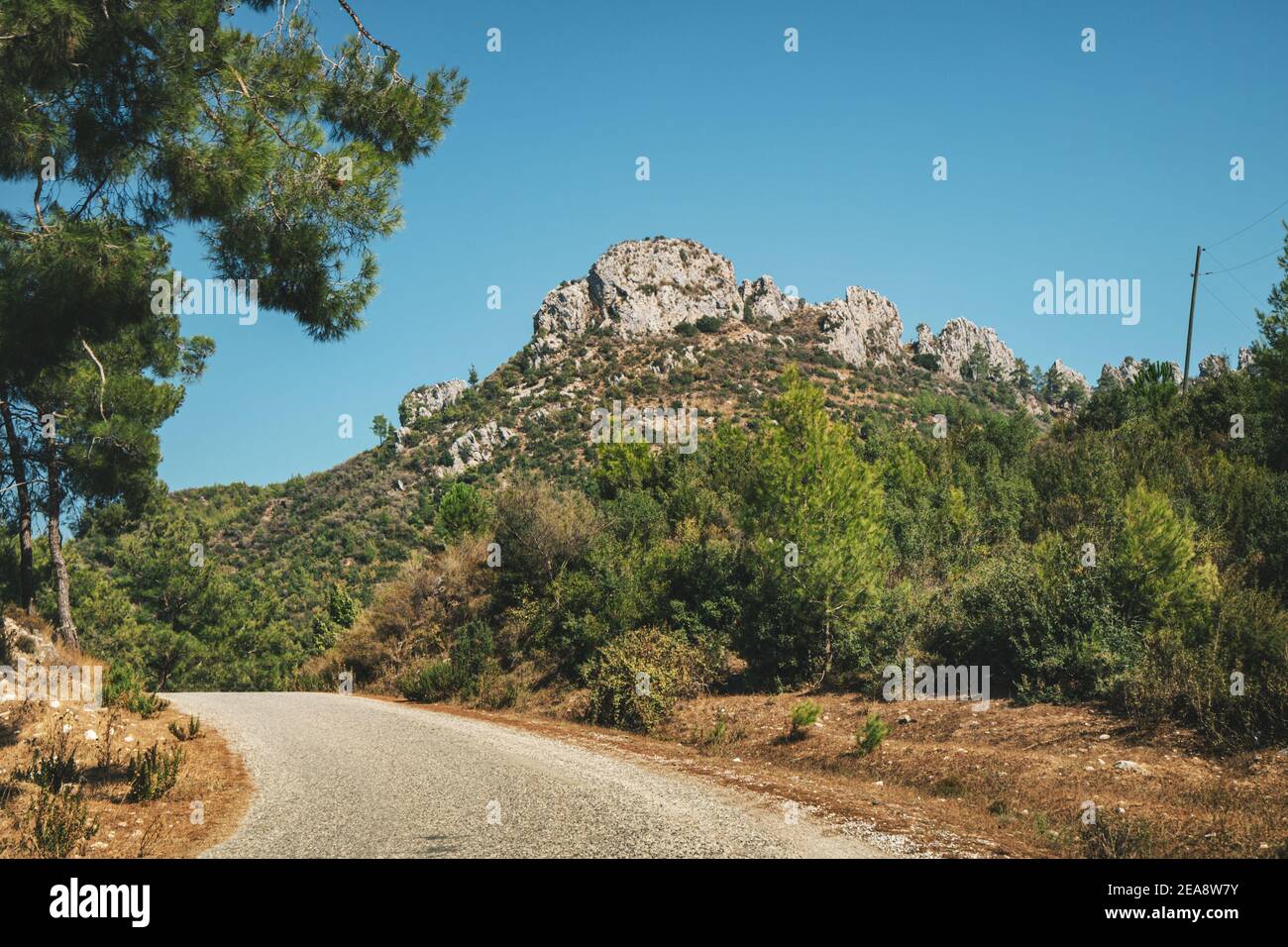 A winding Asphalt road with a view of a lonely mountain with a rock in ...