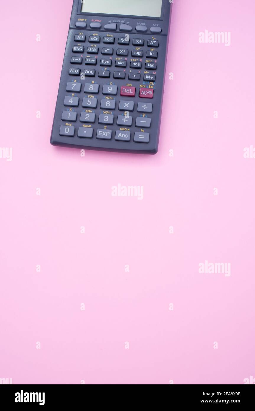 Vertical shot of a scientific calculator on a pink surface with space ...