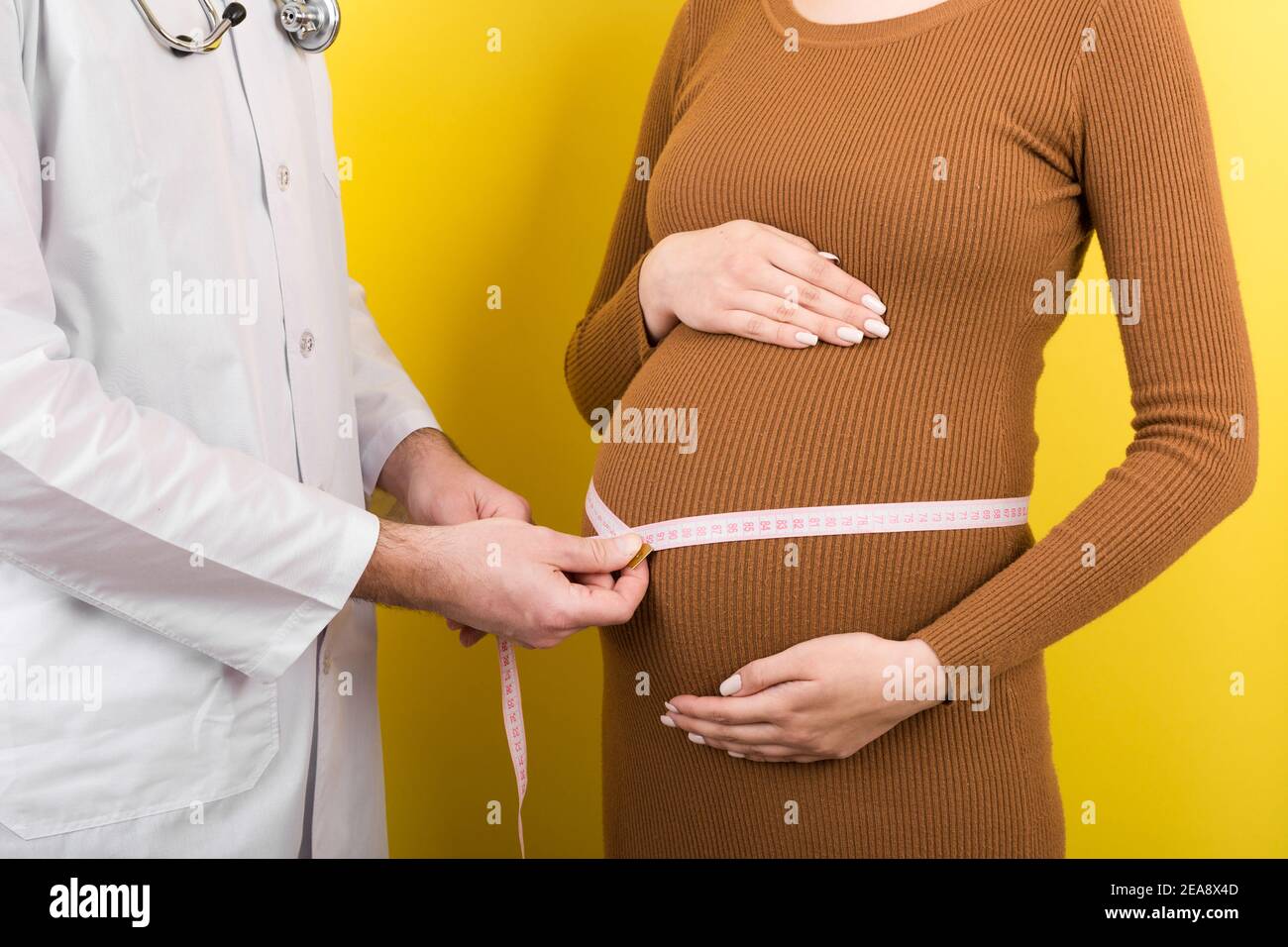 happy beautiful pregnant young woman touching her bare tummy while a ...