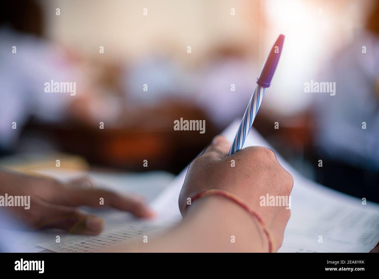Hand of student is taking exam and writing answer in classroom for ...