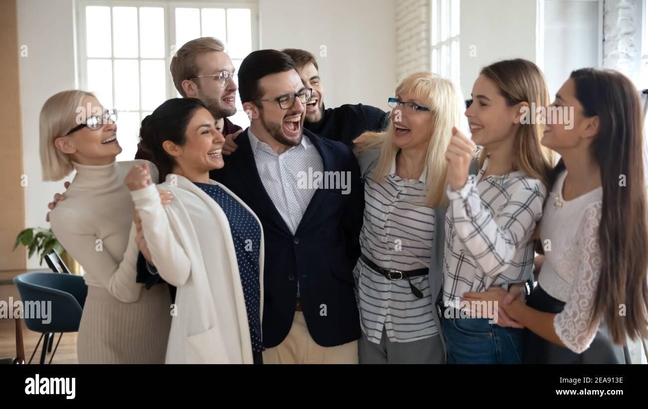 Group of happy employees of different generations hugging together ...