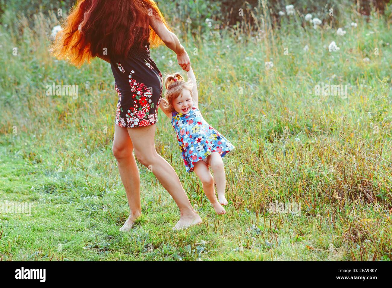 Cheerful mother rotating twisting making circle with her little ...