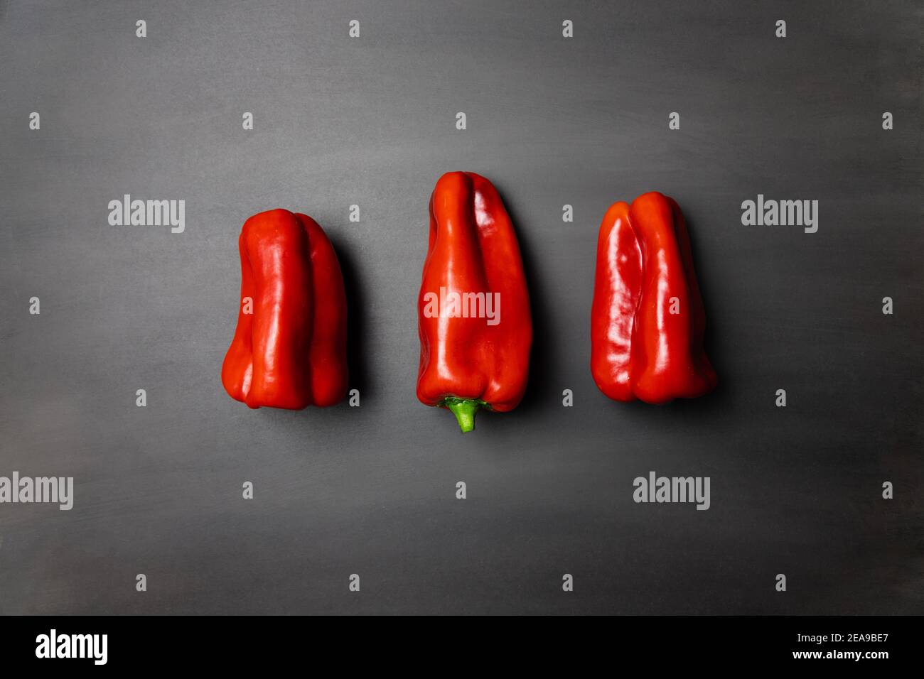 Three red peppers on dark, black background with copy space. Colorful ...
