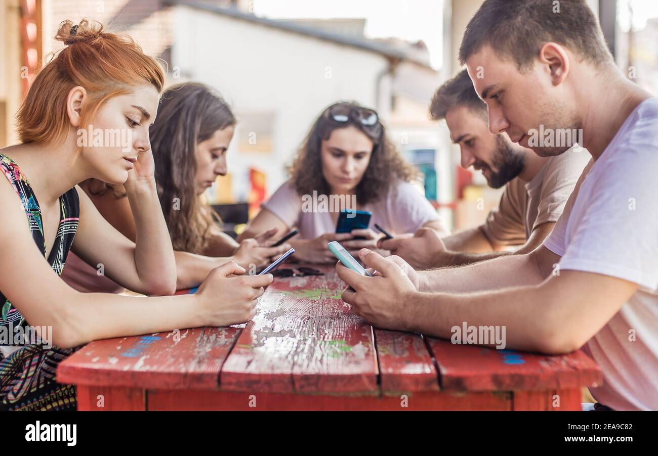 Alienation addiction. Group of friend sitting in cafe and typing on ...