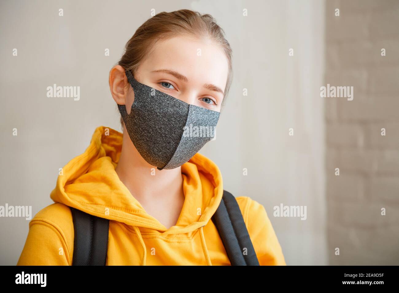 Happy student on brick wall background with copy space. Young beautiful ...