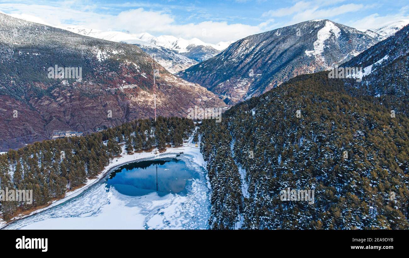 Aerial view of the lake Engolasters surrounded by a forest on a winter ...