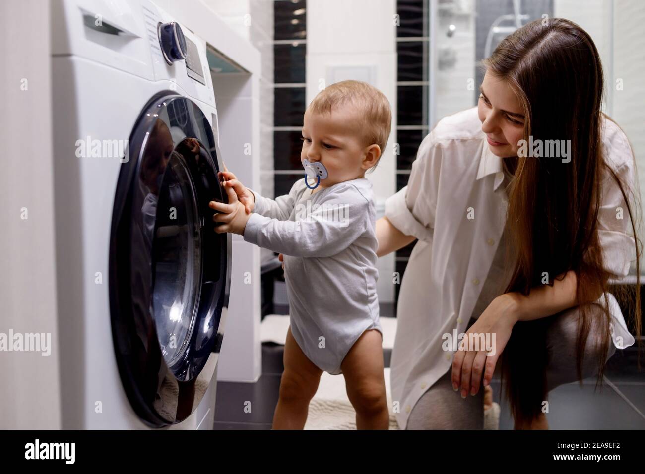 Woman with infant child using washing machine at home Stock Photo - Alamy