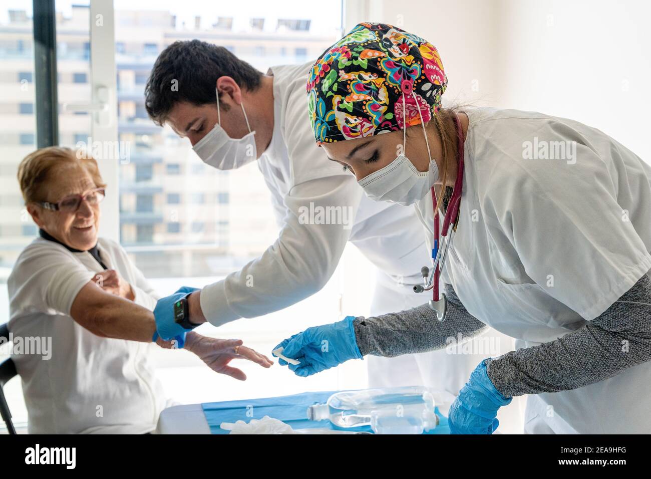 Side view of doctors in protective masks taking blood samples from ...