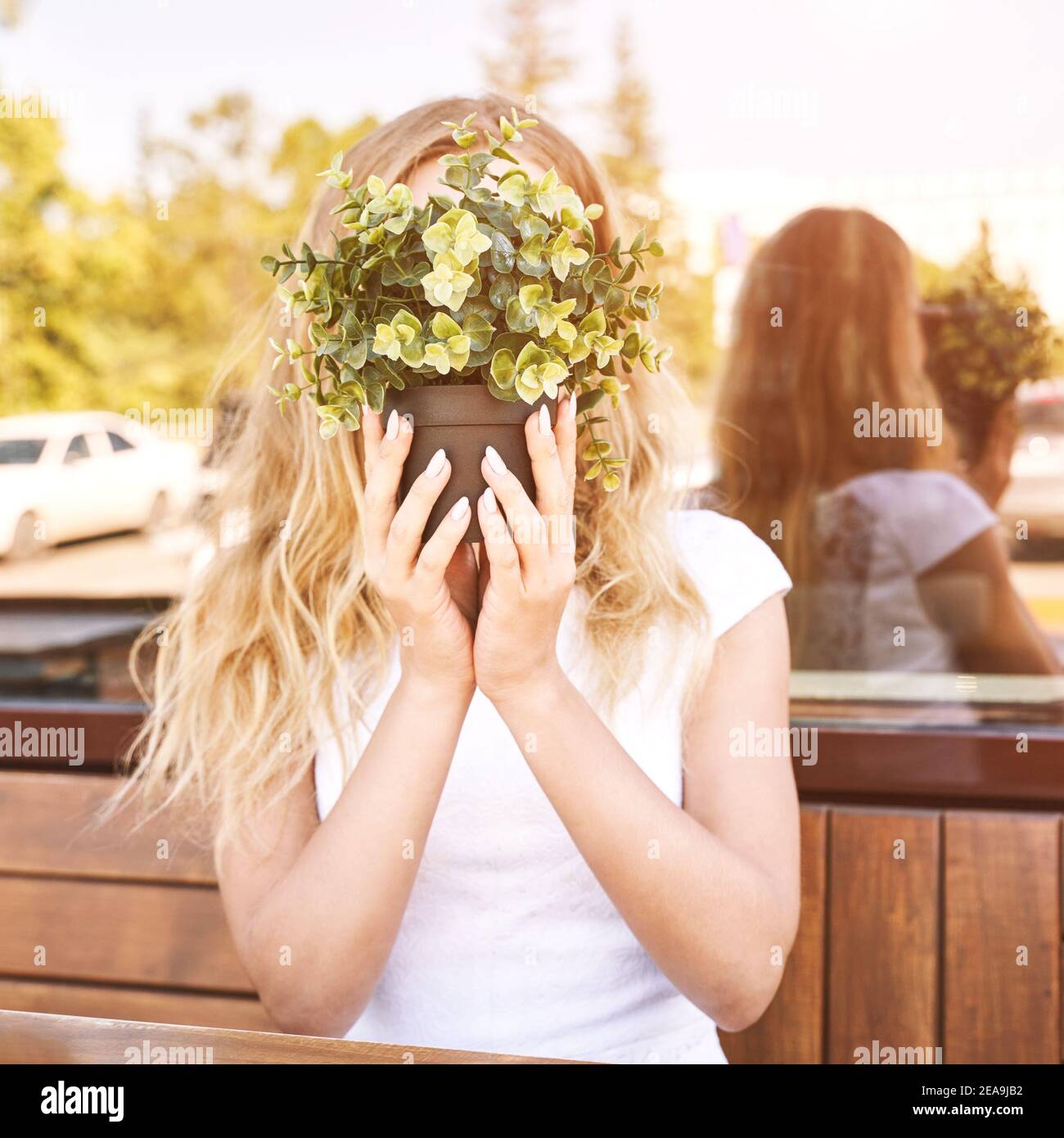 Pretty young woman hide face by green. Outdoors anonymity portrait ...