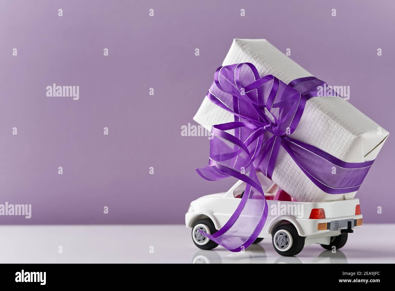 Present in the car like white gift with purple ribbon Stock Photo - Alamy