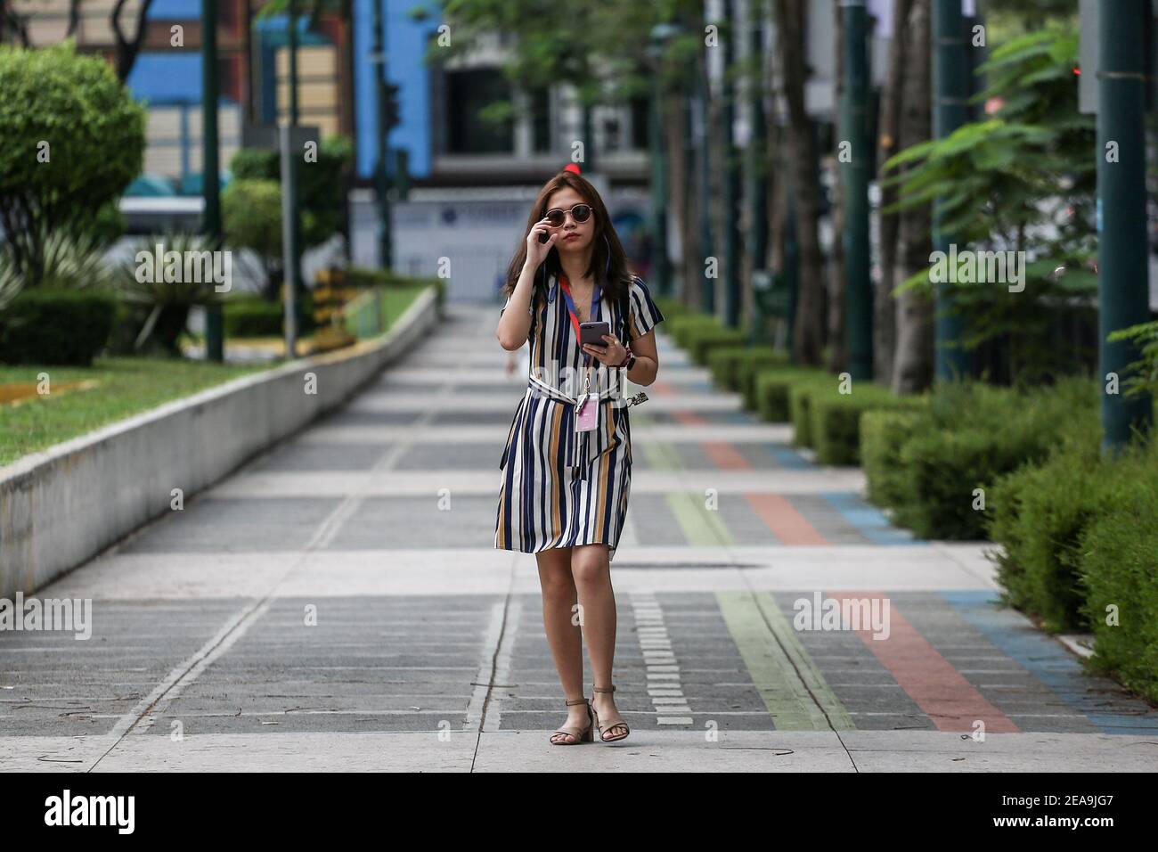 A woman walks alone along a sidewalk in Bonifacio Global City during ...
