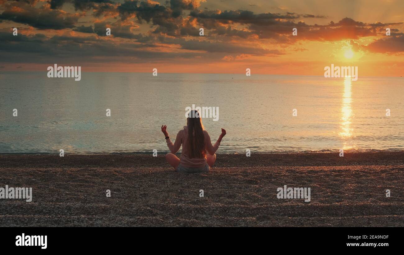 Full shot of woman meditating on the seashore. Back view Stock Photo ...