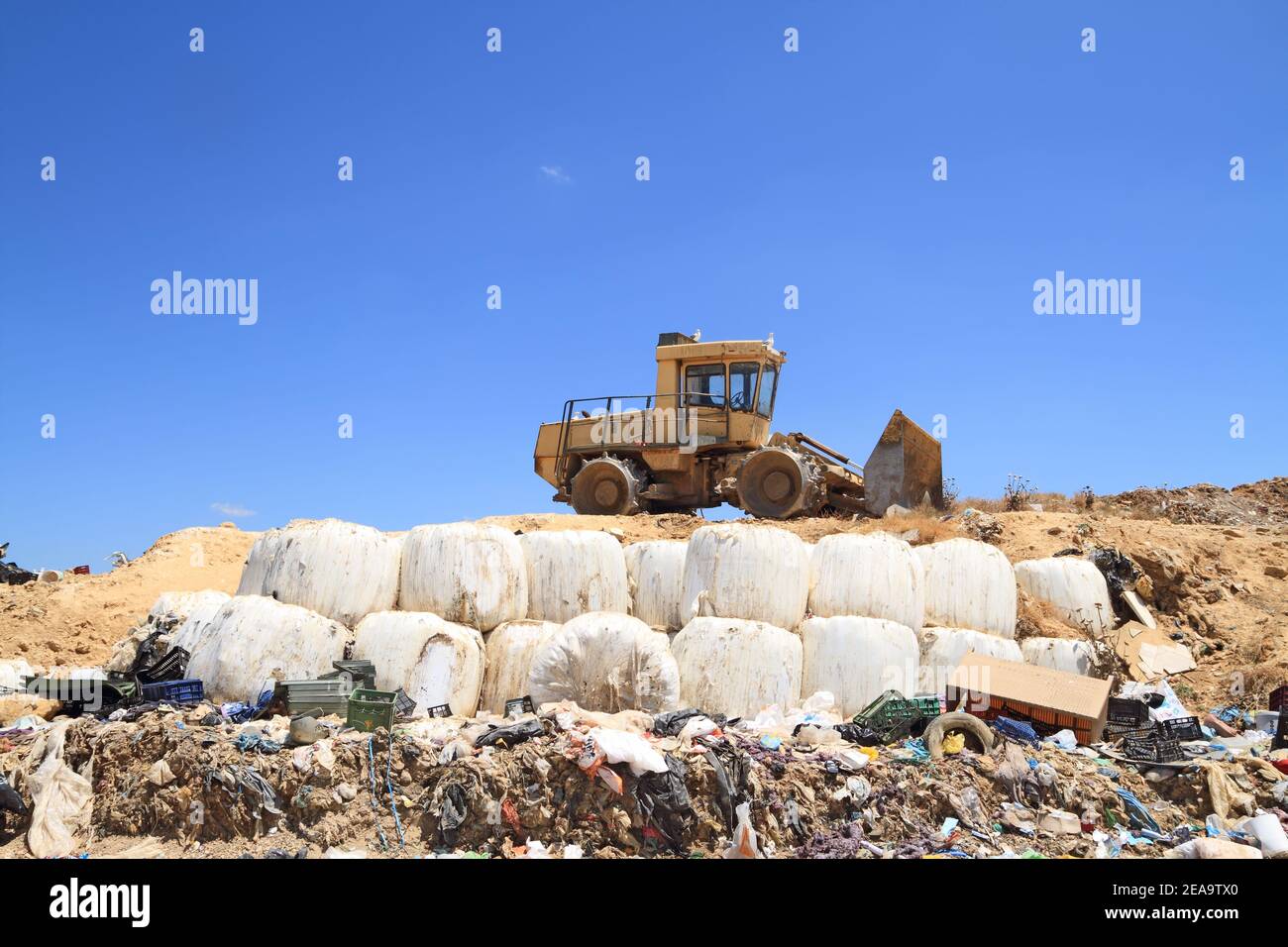 Bulldozer in landfill over garbage dump Stock Photo - Alamy