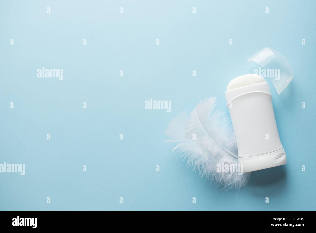 Antiperspirant deodorant on blue background with white feathers. copy ...