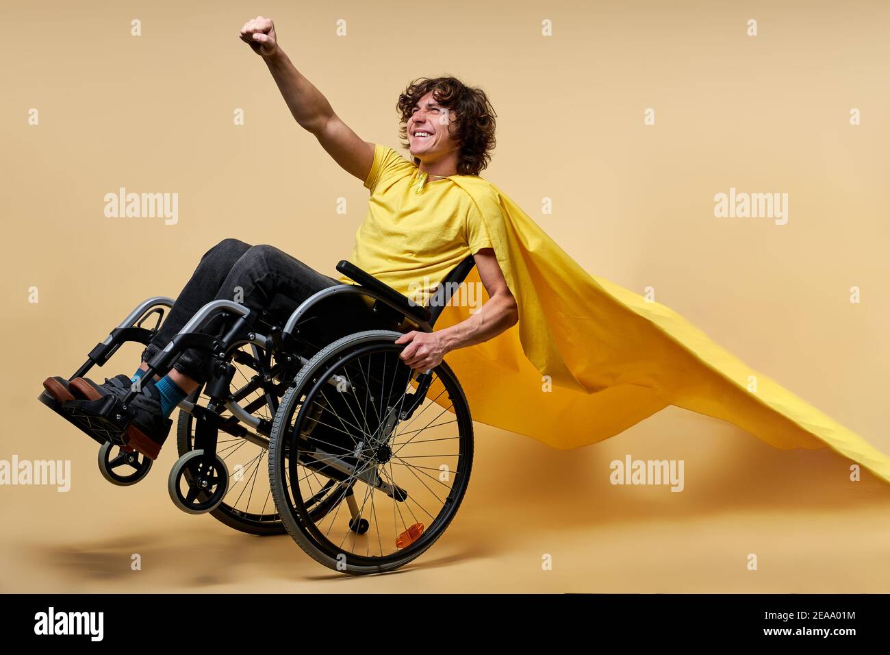 happy disabled man in yellow cloak pretend to be superhero, raising ...