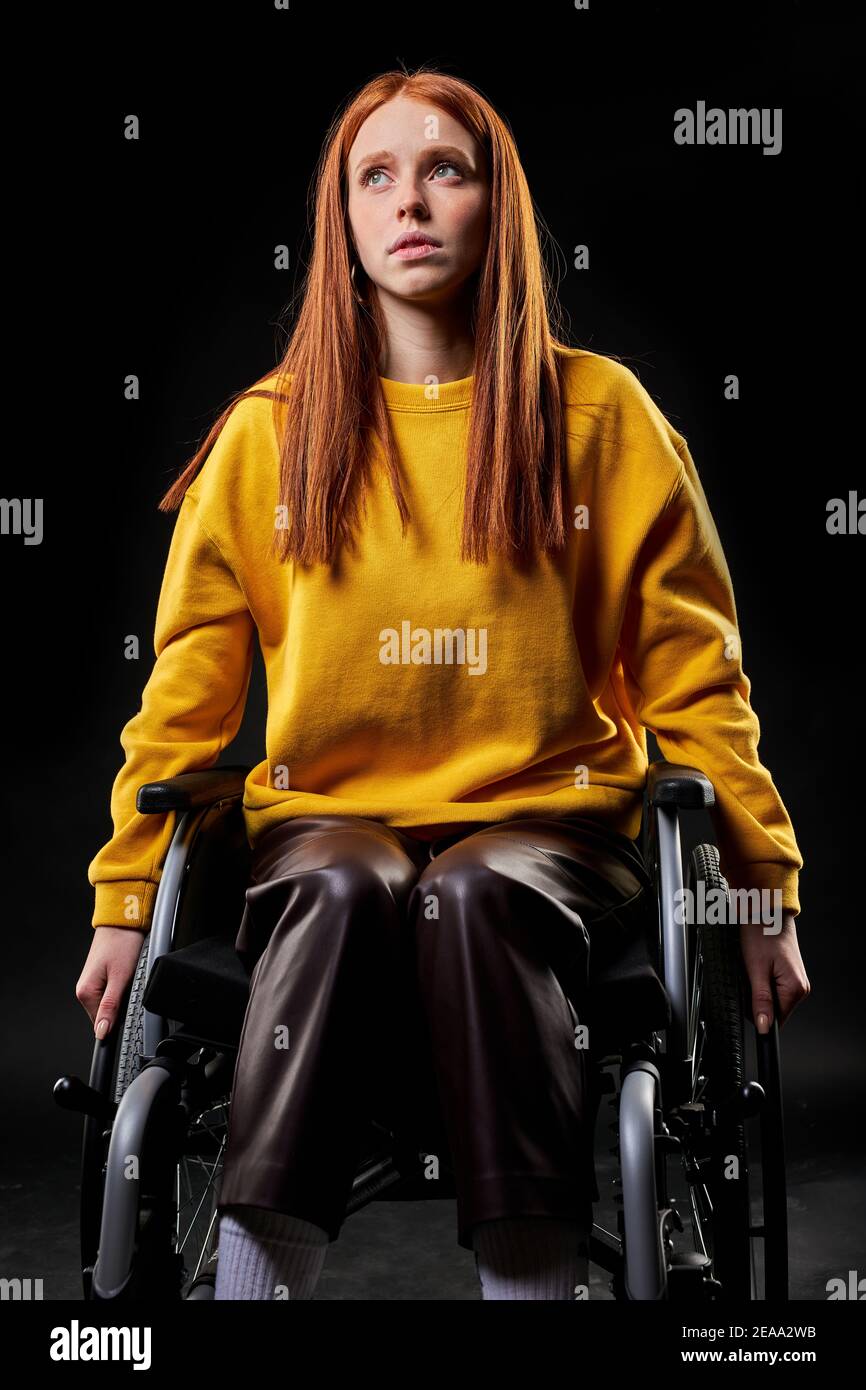 disabled handicapped redhead woman sits looking up, dreaming, having ...