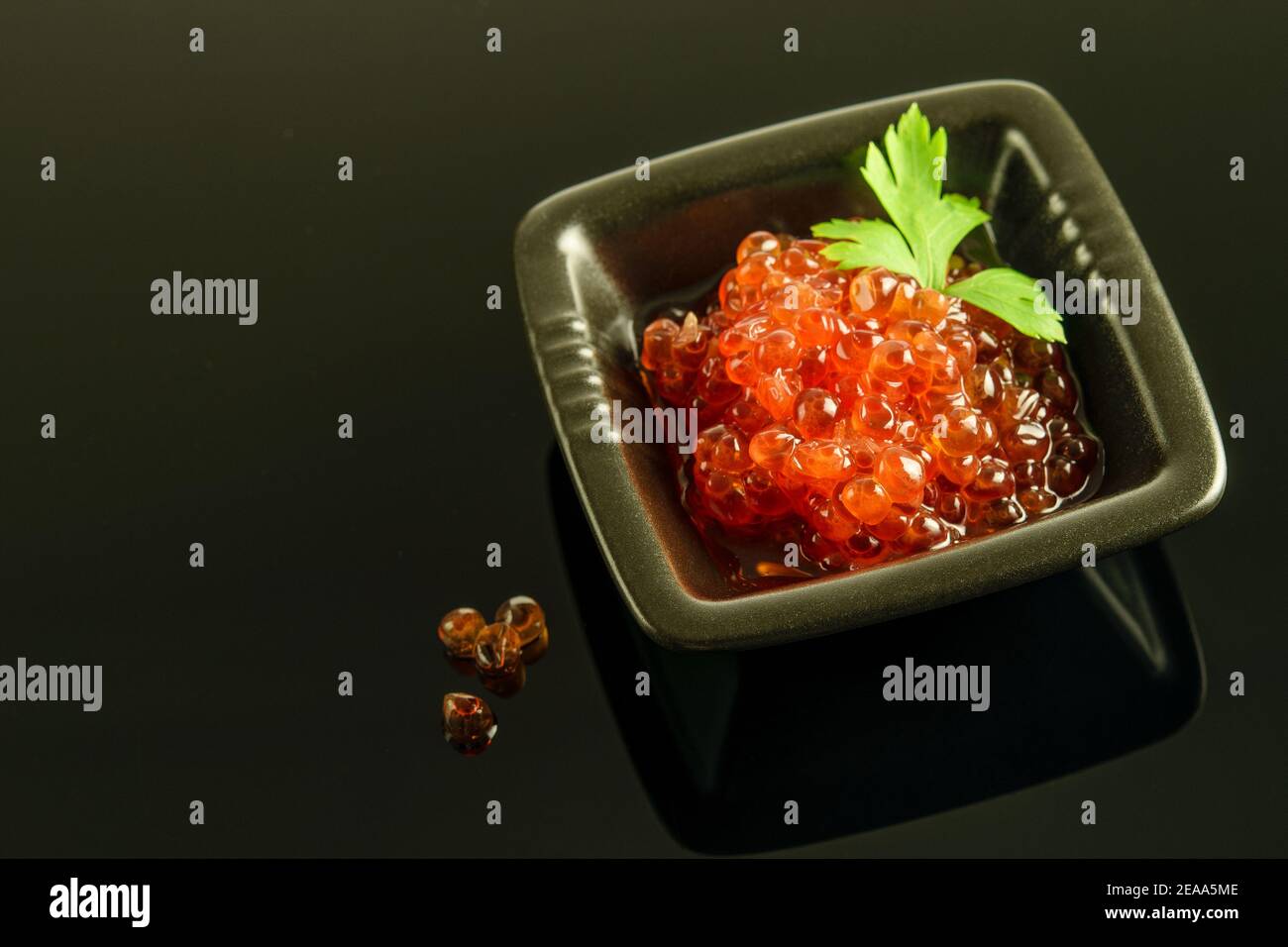 Red caviar with green parsley in the littles black bowl on the black ...