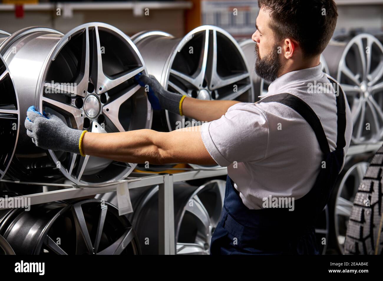 side view on bearded male auto mechanic repairman examining car rims ...
